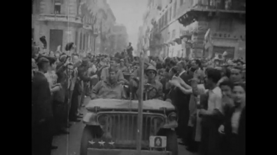 ITALY: 1940s: crowd in street wave flags at military vehicle. People ...
