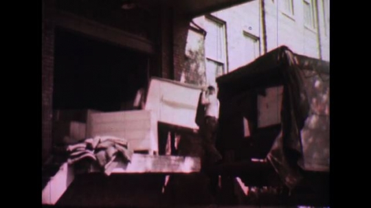 United States: 1950s: Men move large box into van. Train transports ...