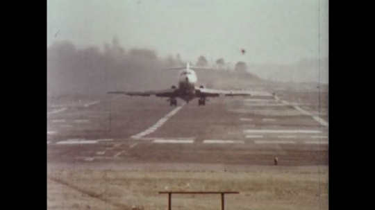 UNITED STATES 1970s: Plane takes off, zoom out, plane flies overhead / Flight control tower ...