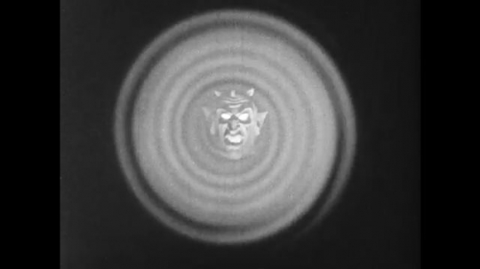 1950s: UNITED STATES: scary face in circles. Dark room and shadows. Boy ...