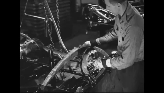 1950s: Vehicle chassis roll down assembly line in automotive factory ...
