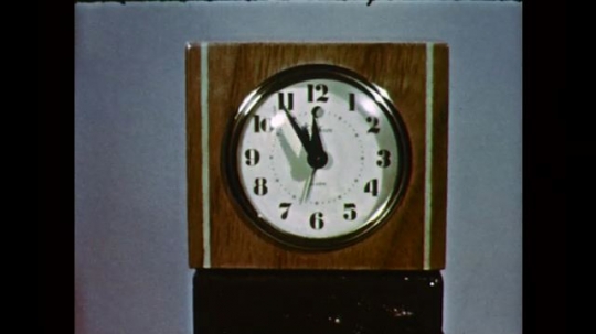 1950s: UNITED STATES: speeding hands on clock face. Man speaks to ...