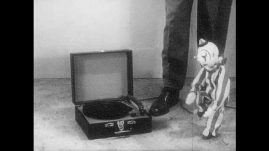 1950s: Marionette walks around phonograph and looks. Puppet touches ...