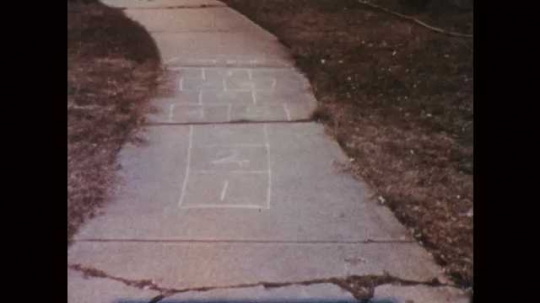1950s: Hopscotch court on sidewalk. Young girl completes hopscotch ...