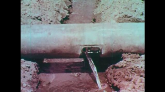 1950s: Water flows out of pipe. Sprinklers water field. – Archival Footage