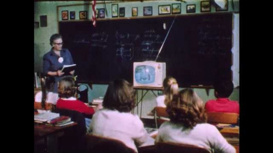 1960s: Children in classroom watch TV. Pilots sit in cockpit, speak ...