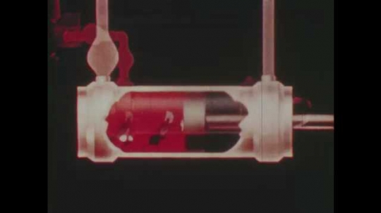 1950s: UNITED STATES: flow of liquid inside cylinder. Character runs ...