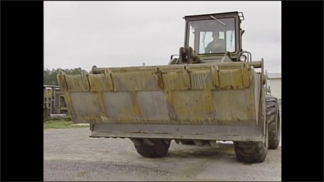 2000s: Industrial buildings. Puddle in front of pile of gravel. Front ...