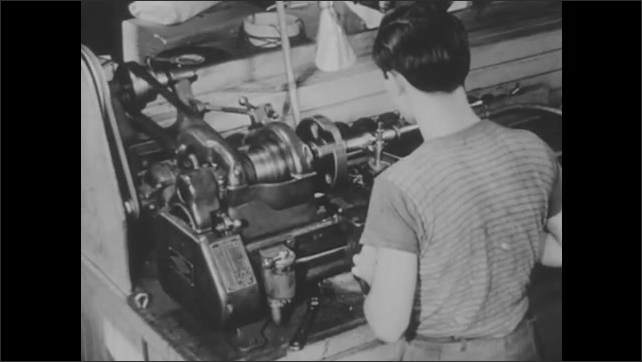 1940s: UNITED STATES: man uses lathe. Motor in operation on lathe ...