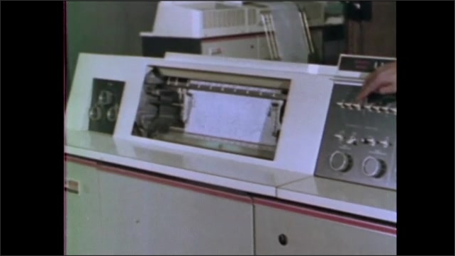 1970s: soldier looks at paper, types at desk near computers with ...