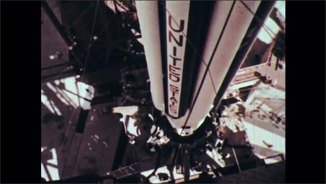 1960s: Stationary rocket in upright position. People busy at bottom of ...