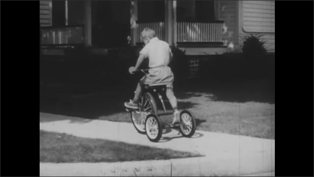 1950s: UNITED STATES: boy sits on bike. Boy turns bike around on ...