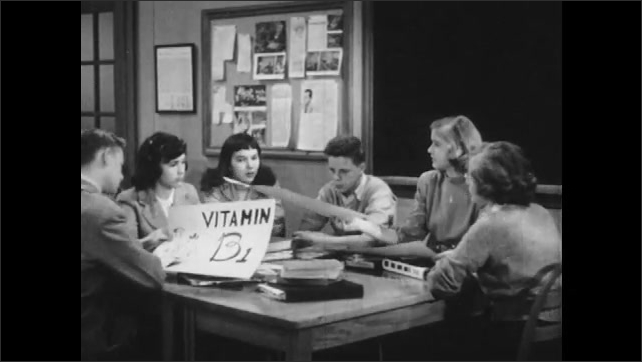 1940s: Classroom. Students sit in group and talk. Girl passes out ...