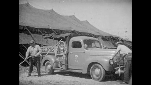1940s: UNITED STATES: circus people carry water on fire truck. Man ...