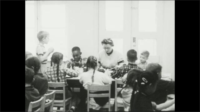 1950s: Boys and girls raise arms and smile in classroom. Boys and girls ...