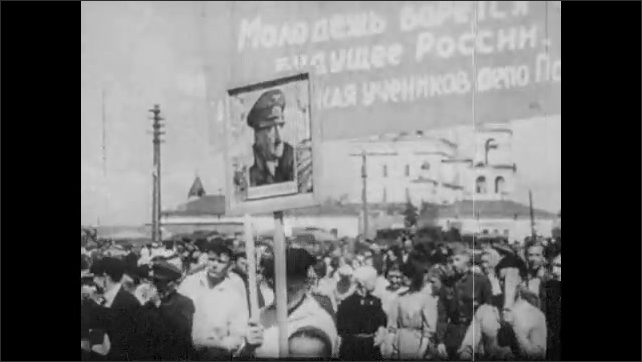 1930s: People hang poster of Adolf Hitler in window. Woman hands out ...