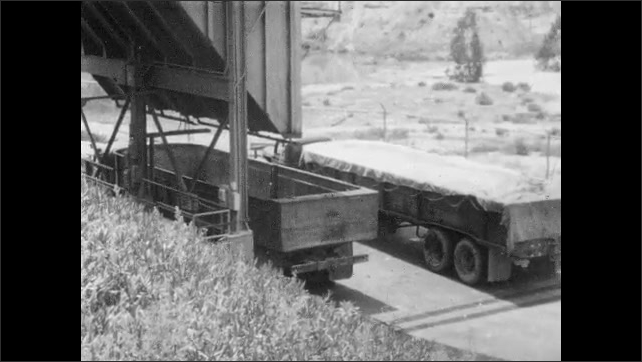 1950s: Tractor trailer parks under elevated hopper. Driver exits and ...