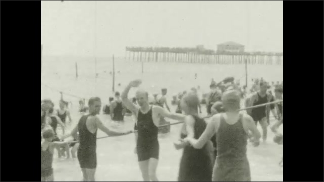 1920s: UNITED STATES: swimmers hold on to rope at seaside. Swimmers ...