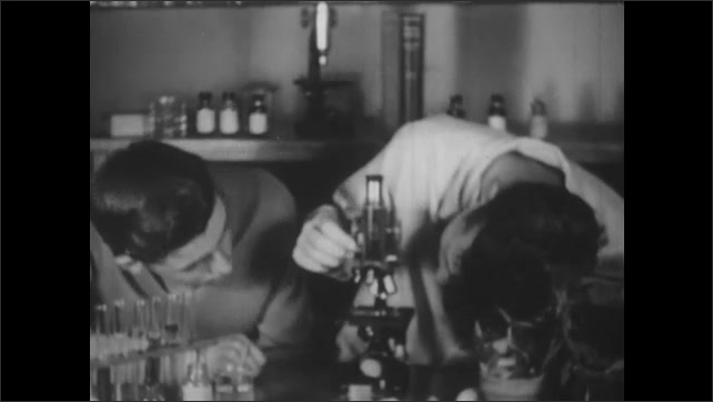 1940s: Lab. Young men put slide onto microscope and lower lens. Teenage ...