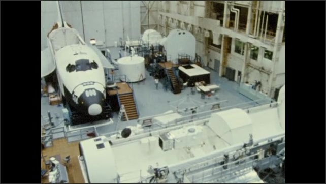 1980s: People in meeting at NASA. Space Shuttle under construction ...