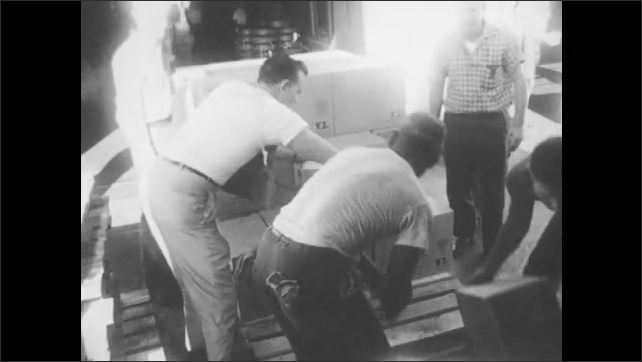 1960s: Men load roller conveyors into truck. Men load boxes into truck ...