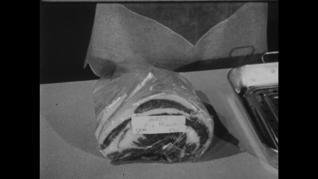 UNITED STATES: 1950s: hands unwrap meat. Lady places meat in roasting ...