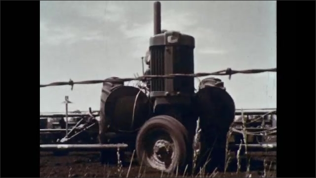 1960s: UNITED STATES: farmer drives tractor in field. Tractor in corn ...