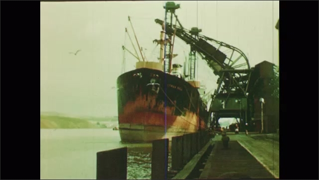1950s: large cargo ship passing sailboat and another cargo ship, pulley ...