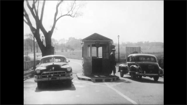 1950s: UNITED STATES: car arrives at visitor booth. Uniformed officer ...