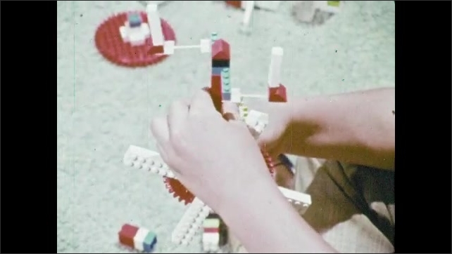1970s: Boy snaps stacks of Legos together. Boy constructs spinning ...