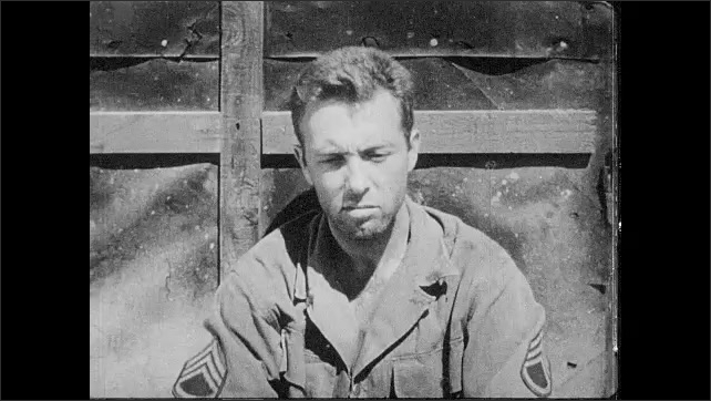 1950s: UNITED STATES: soldier sits on ground in prison camp. Sergeant ...