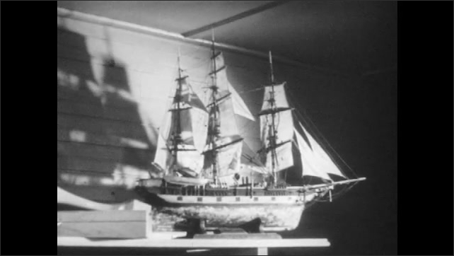 1940s: UNITED STATES: model of ship on shelf. Shadow of ship. Boy ...