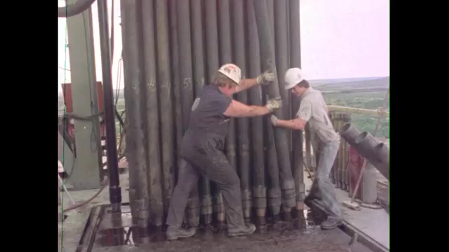 1970s: Oil well, men wear hard hats, uniforms, overalls. Men move ...