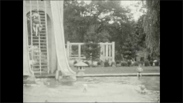 1920s: UNITED STATES: outdoor pool and slides. Lady carries bucket of ...
