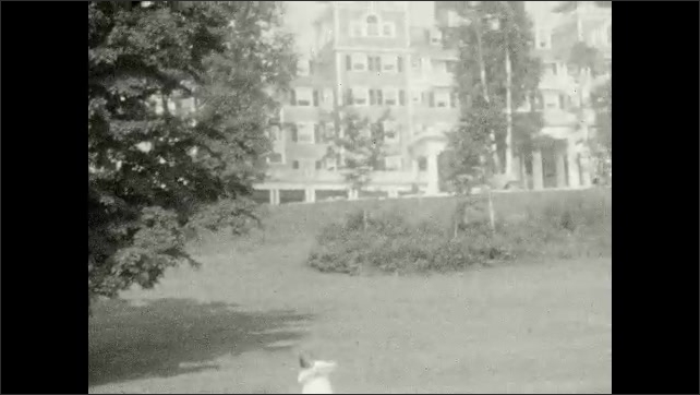 1920s: UNITED STATES: park in gardens. Car by large buildings. Girl in ...