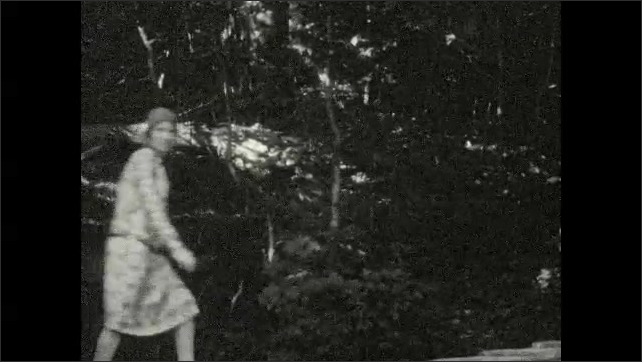 1920s: UNITED STATES: girl walks in woods. Family cross bridge over ...