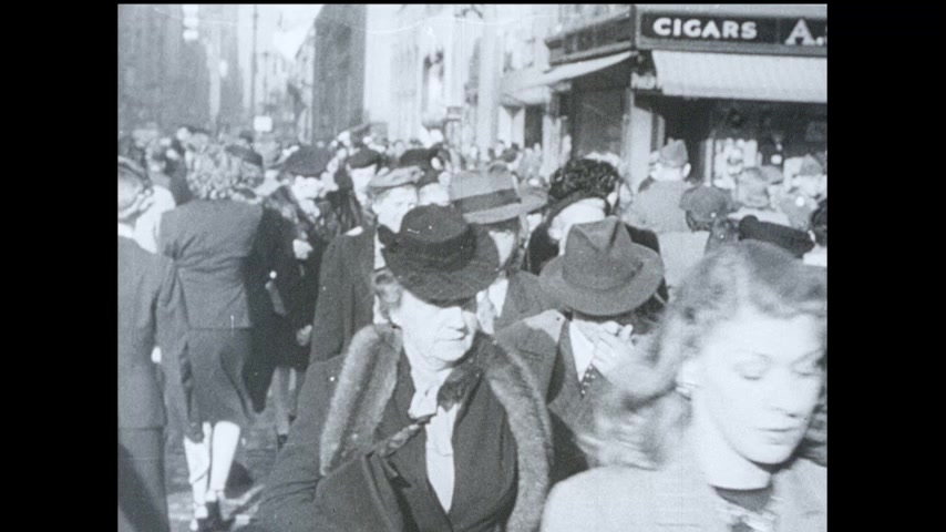 1950s: Crowd of people walking down busy street. Cows herded together ...