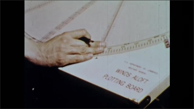 1960s: Man sits in front of machine, looking at readout and writing on ...