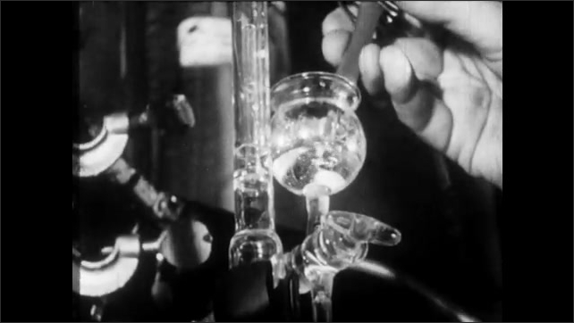 1940s: Male scientists stand in laboratory. Beakers and flasks bubble ...