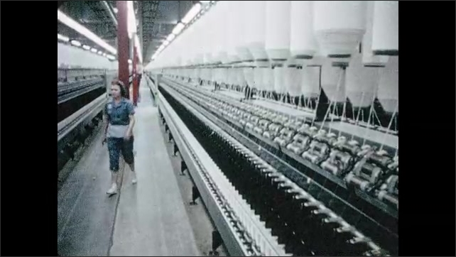 1960s: Saco-Lowell machines spin thread. Woman walks down aisle between ...