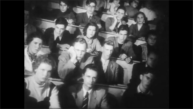 1950s: Old professor talks. University students sit in lecture hall ...