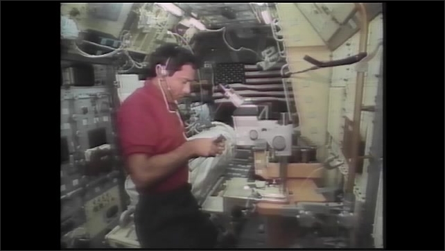 1990s: Space shuttle launches. Astronaut works in cabin. Man looks in ...