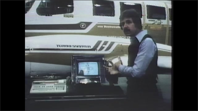 1980s: Diagram of airplane on computer monitor. Man stands in front of ...