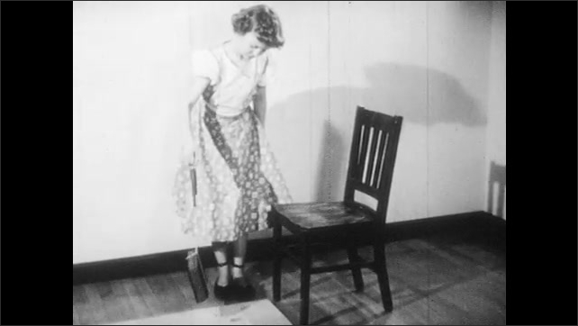 1950s: UNITED STATES: lady lifts heavy book from floor to chair. Close ...