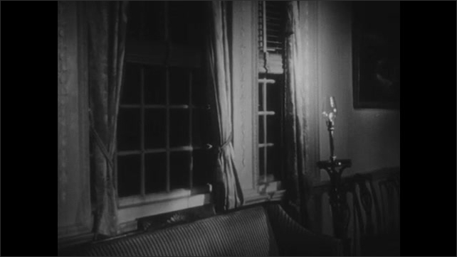 1950s: Lightning flashes outside tall draped windows. Lightning flashes ...