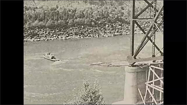 1930s: Boat and barge float down river. Bridge under construction ...