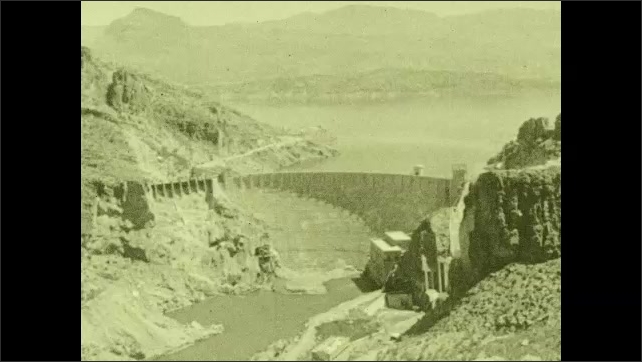 1930s: People build dam. Car drives across top of dam. – Archival Footage
