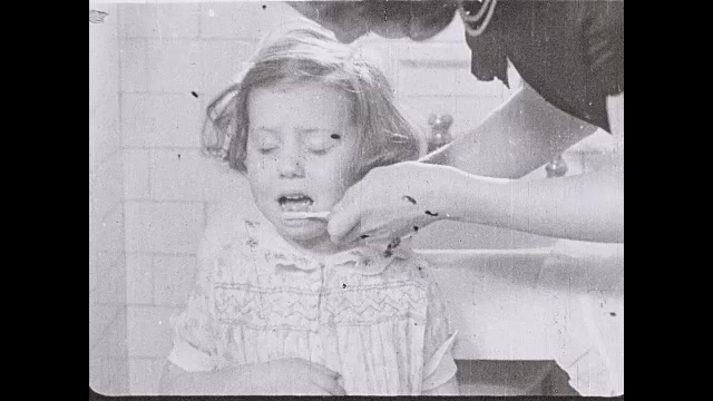 1930s: Woman brushing girl’s teeth. Views of girl brushing her own ...