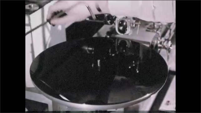 1950s: UNITED STATES: spindle on turntable. Holes on turntable. Man ...