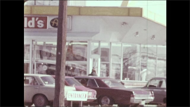 1970s: Person puts gas pump in tank of car at gas station. McDonalds ...